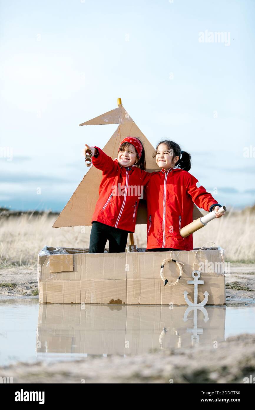 Side view of cheerful kids with handmade spyglass standing in handmade ...