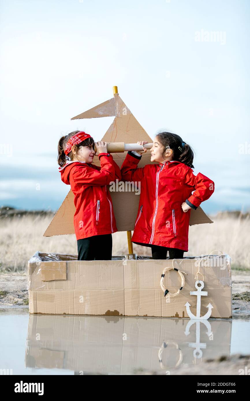 Side view of cheerful kids with handmade spyglass standing in handmade ...