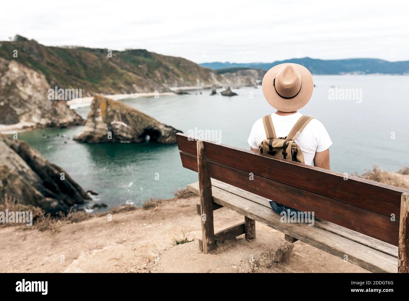 Back view high angle of male explorer in hat sitting on wooden bench ...