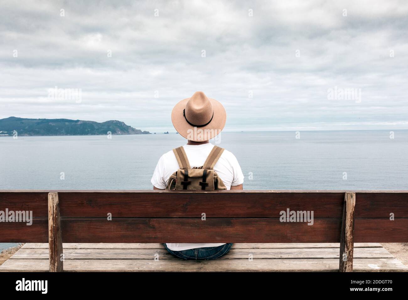 Back view high angle of male explorer in hat sitting on wooden bench ...
