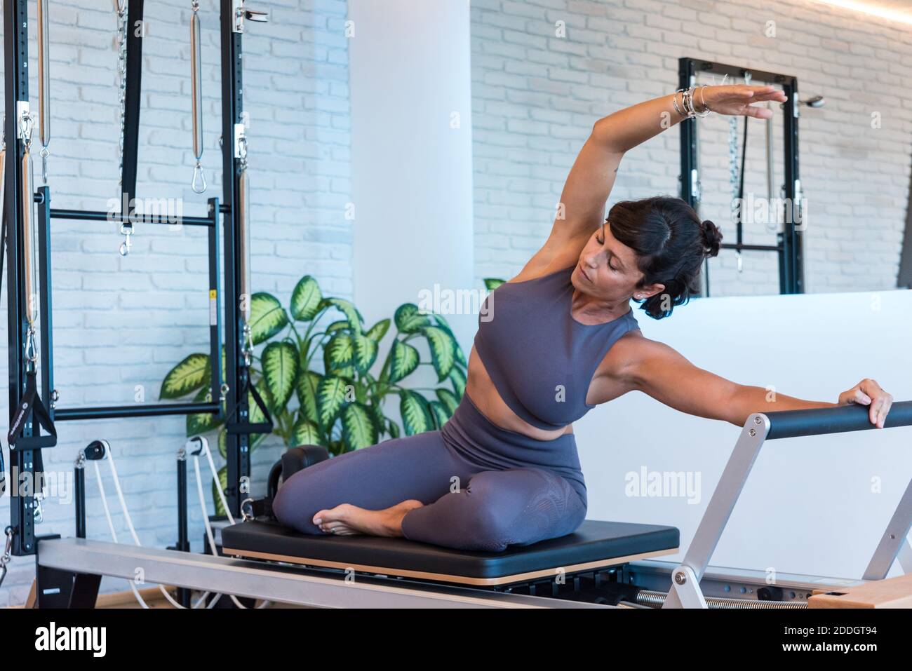 Slim adult female doing Seated Side Bend and stretching body on modern ...