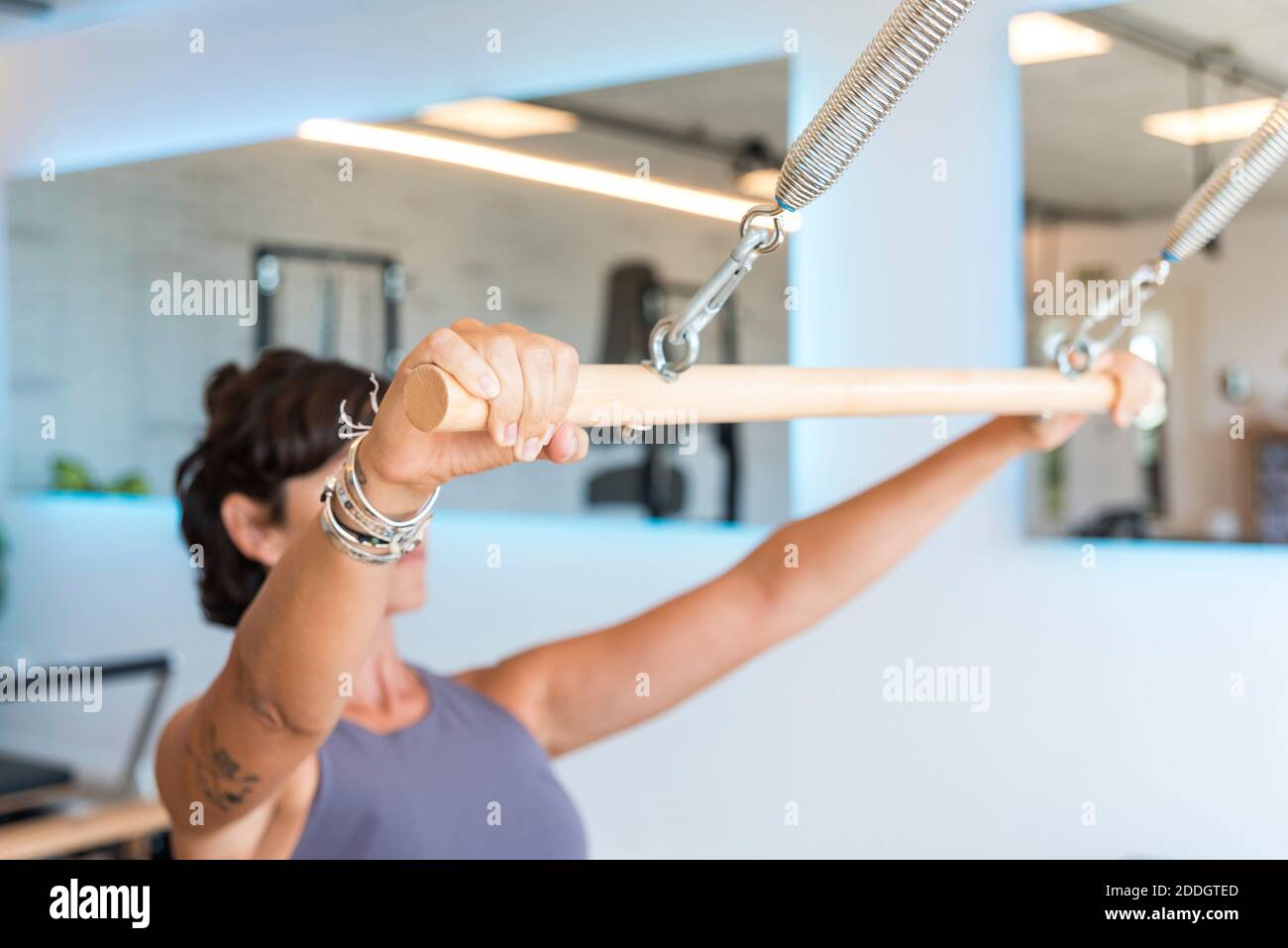 Slim adult female stretching body on modern reformer during Pilates ...