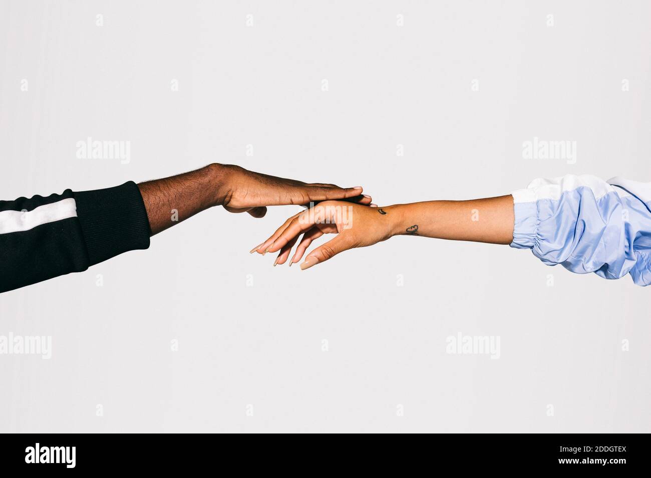 Close-up of a man's black hand on a Woman's white hand over white ...