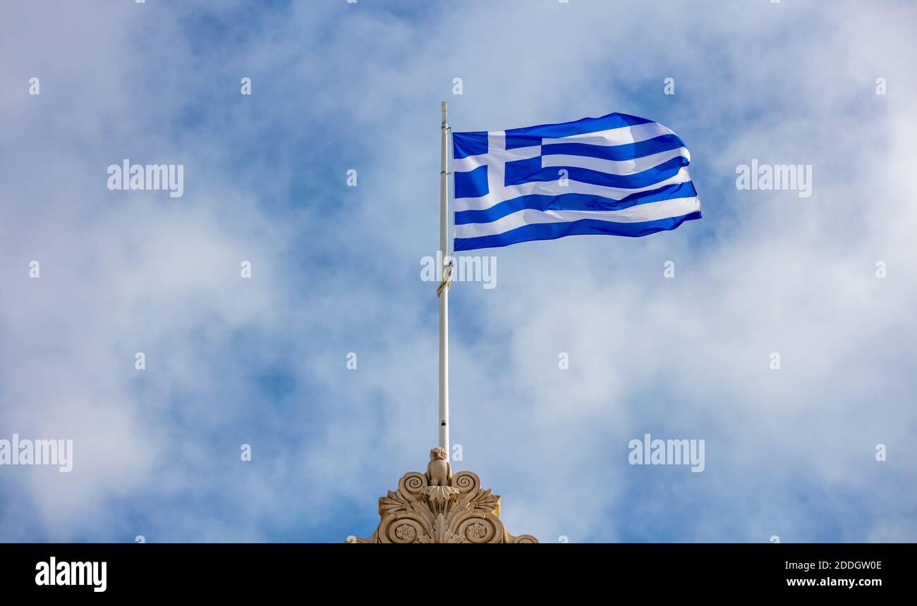 Greek flag waving on pole against blue cloudy sky background, copy ...