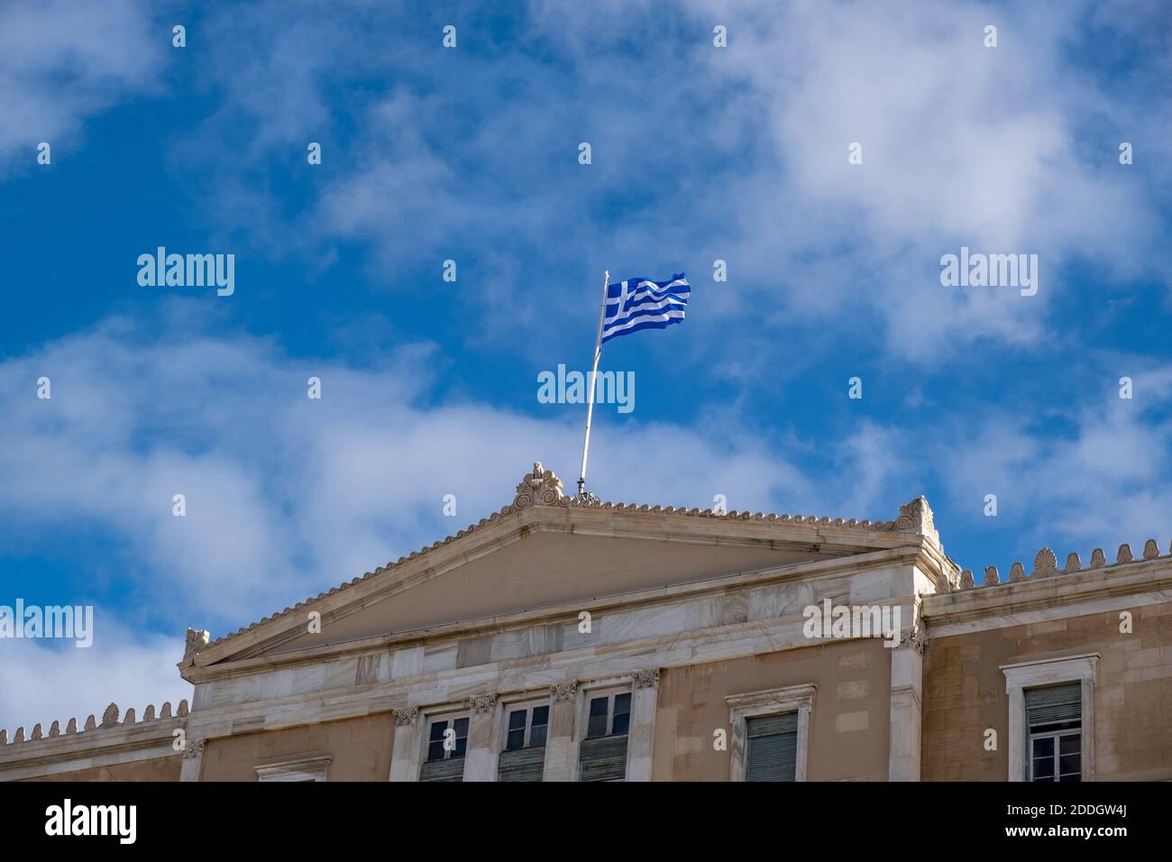 Greek flag waving on pole against cloudy blue sky background, copy ...