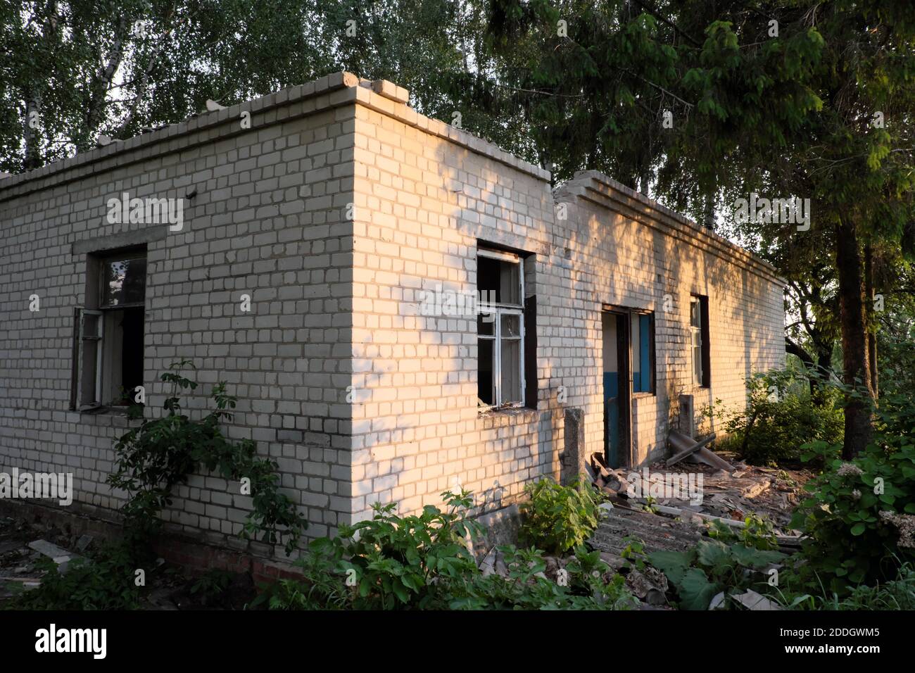 Old destroyed buildings among trees and green grasses. Abandoned ...