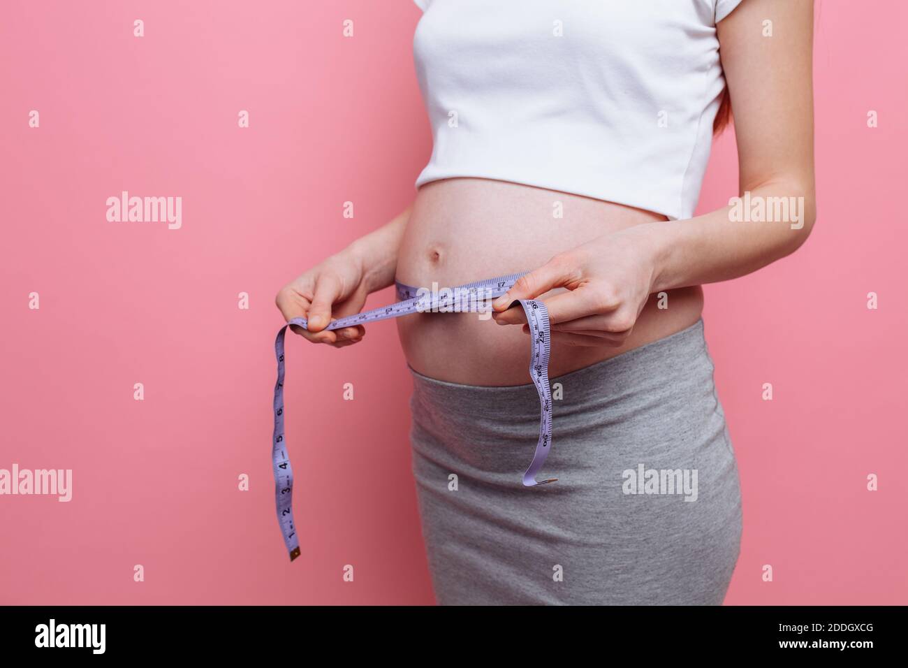 Pregnant woman measuring her big tummy in the third trimester with a ...