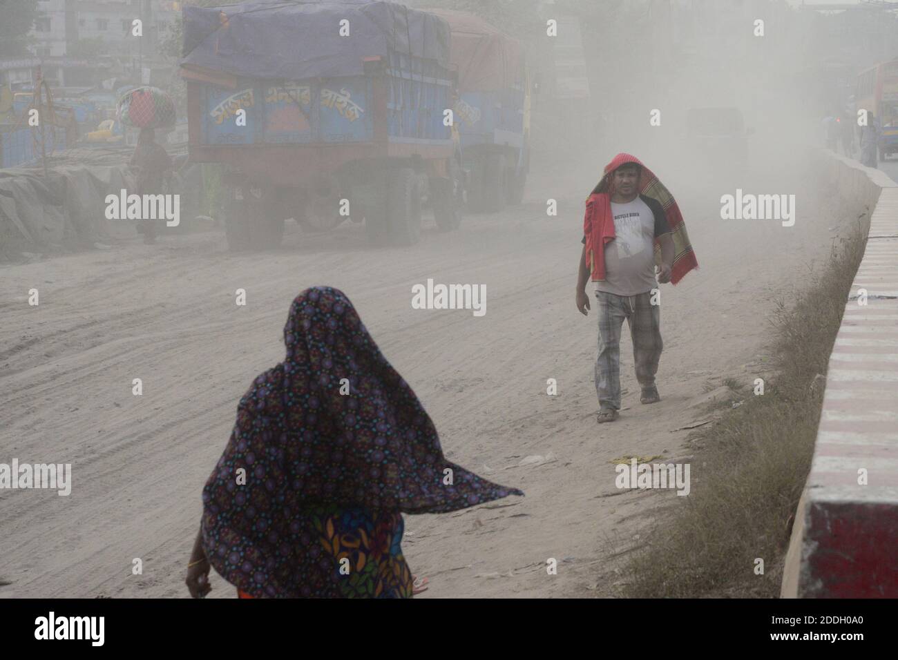 Peoples walk through a dusty busy road in Dhaka, Bangladesh, on ...