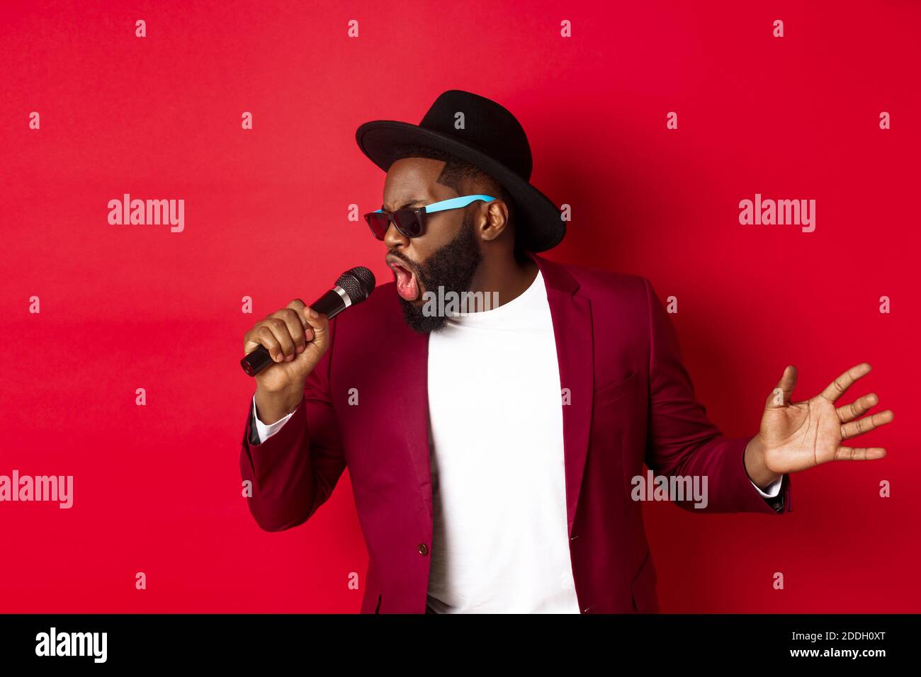 Passionate black male singer performing against red background, singing ...