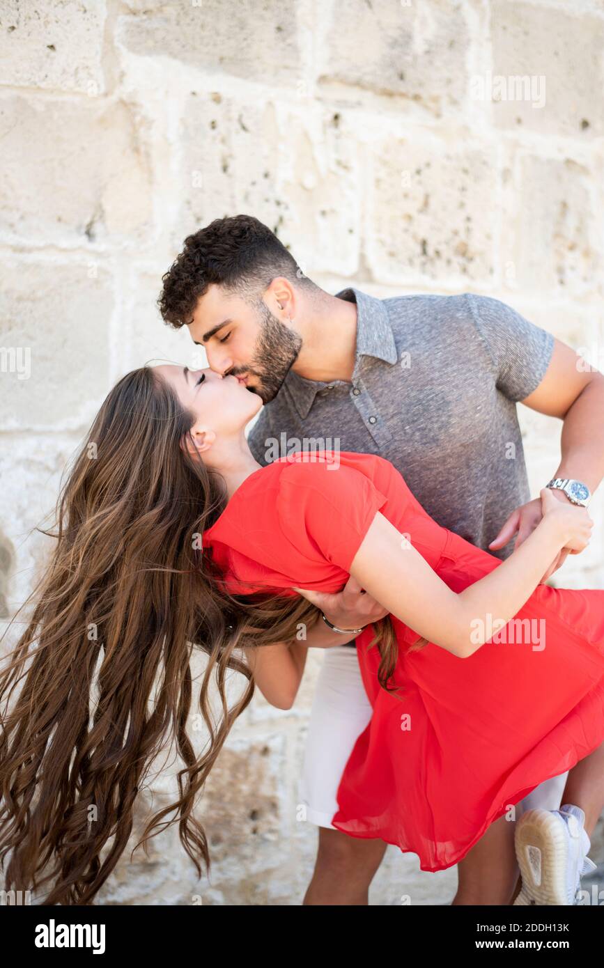 Affectionate young couple kissing in front of an old wall Stock Photo ...