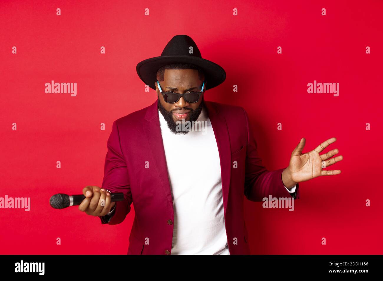 Passionate black male singer performing against red background, singing ...