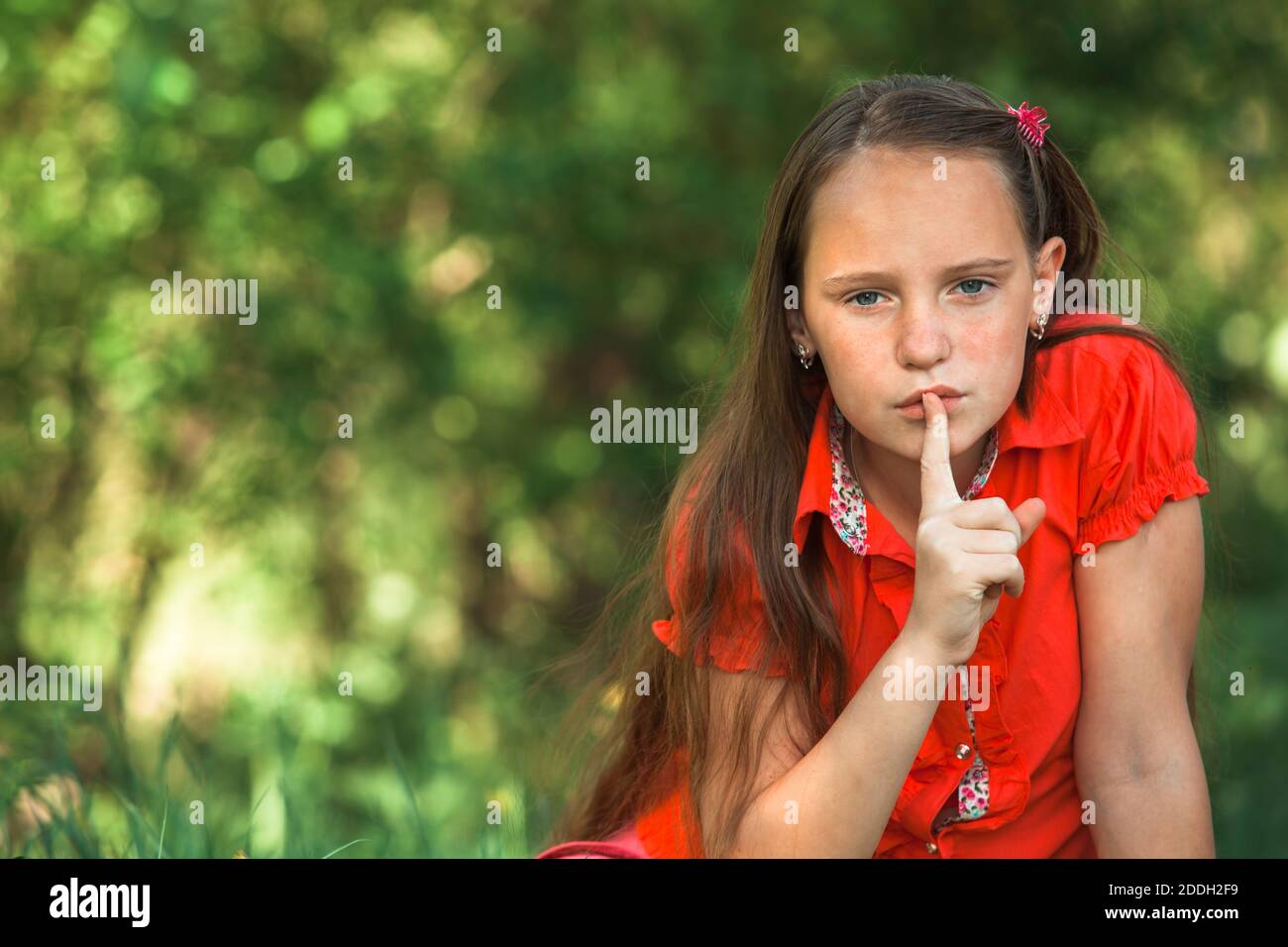 Hushing, teen girl with her finger over her mouth Stock Photo - Alamy