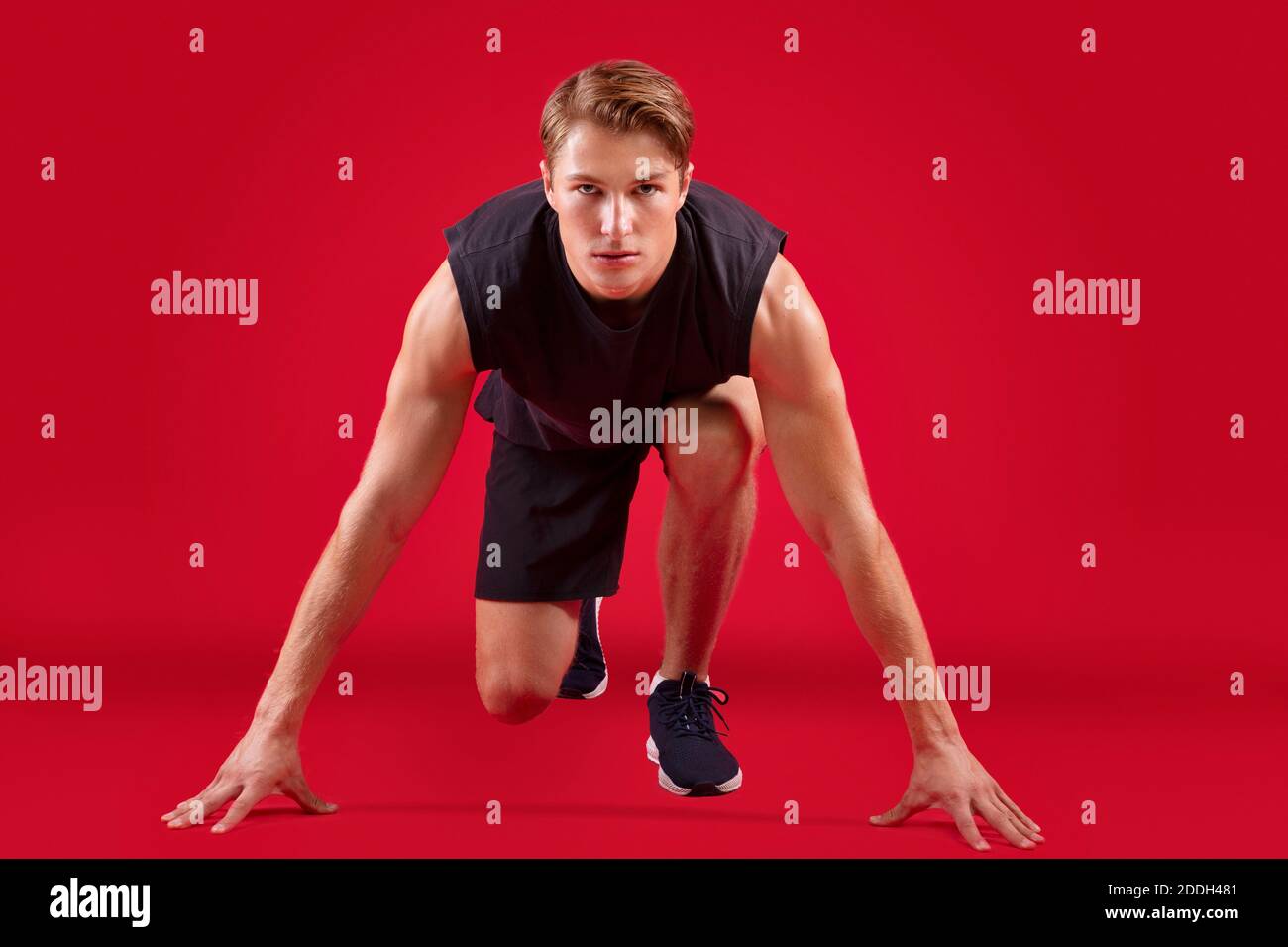 Full length portrait of athletic young runner standing on start over ...