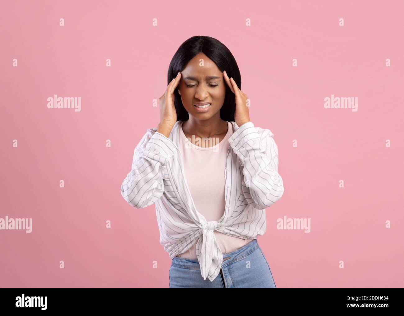 Tired black woman suffering from headache or hypertension on pink ...