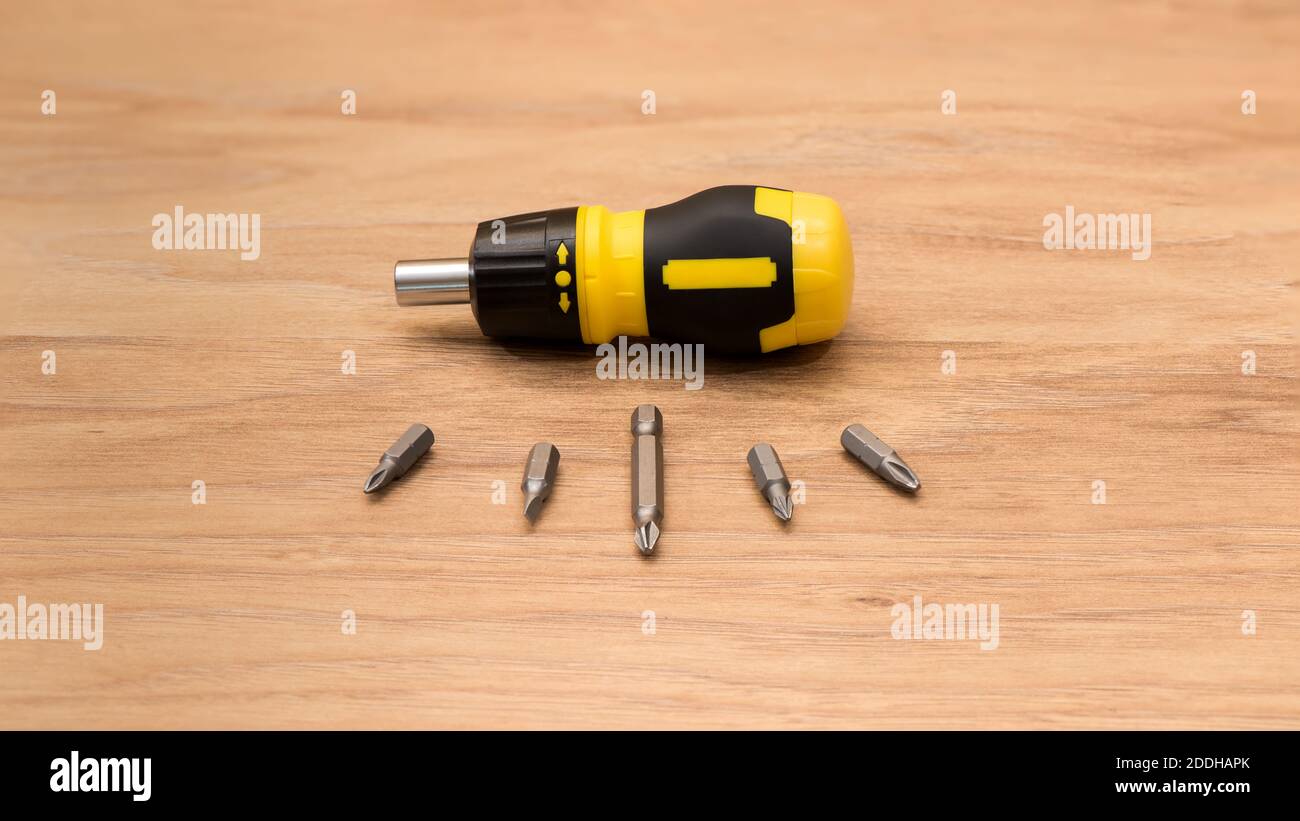 Yellow-black handle screwdriver and bit set still life on wooden ...