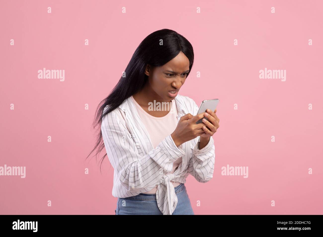 Angry black woman looking at her smartphone with disgust, reading ...