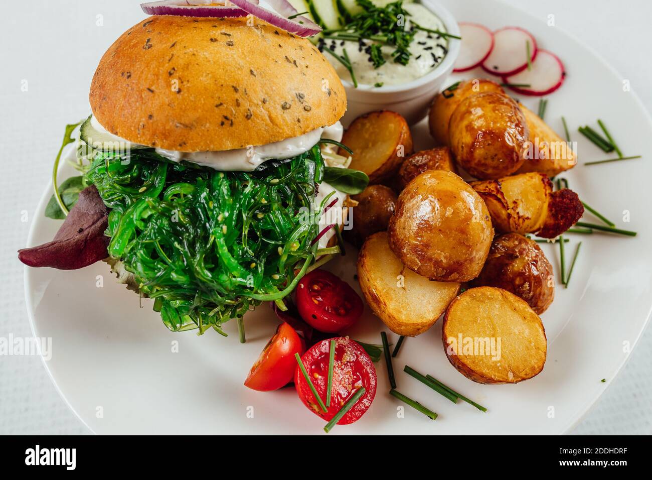 A top view closeup of roasted potatoes with tomato and radish next to a ...