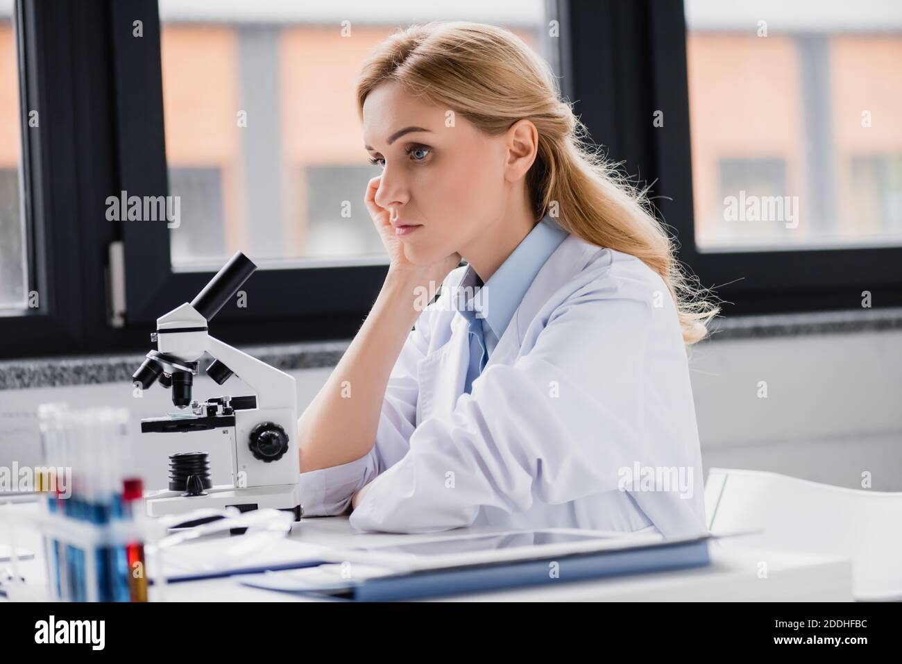 sad scientist leaning on hand near microscope in lab Stock Photo - Alamy