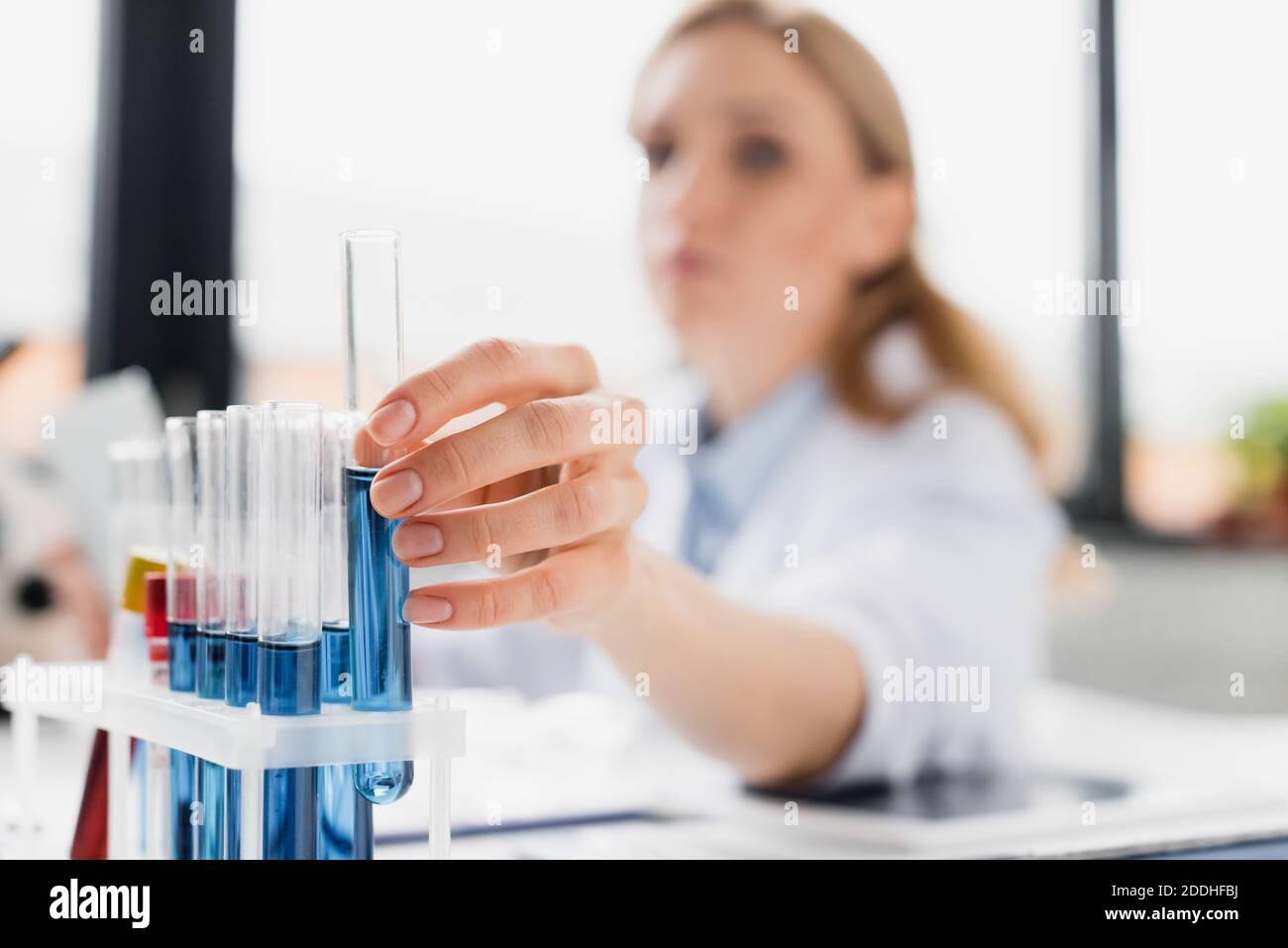 test tube with blur liquid in hand of scientist on blurred background ...