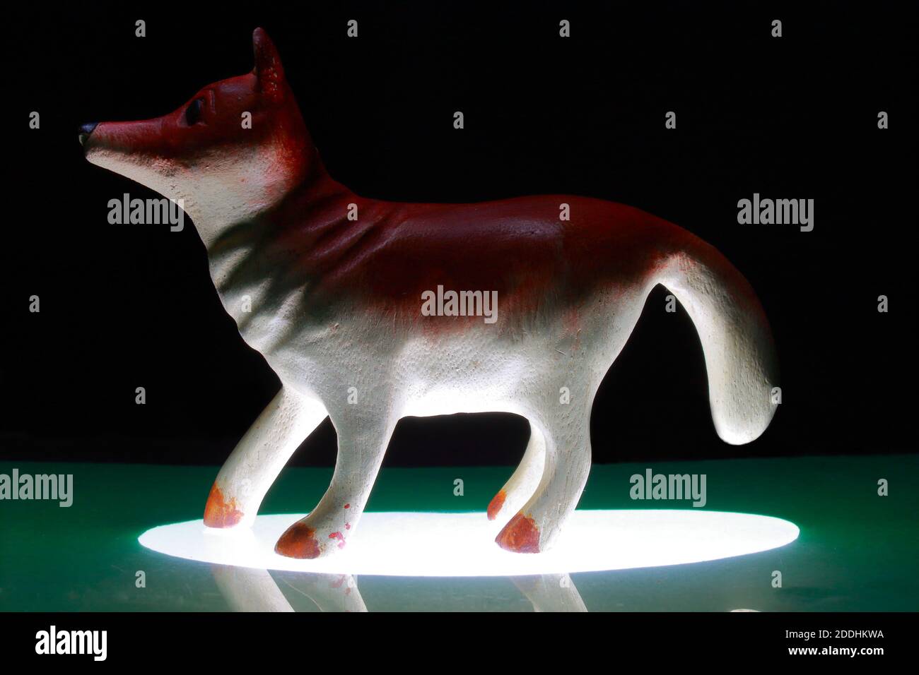 wooden statue of a fox illuminated from below with a ring of light ...