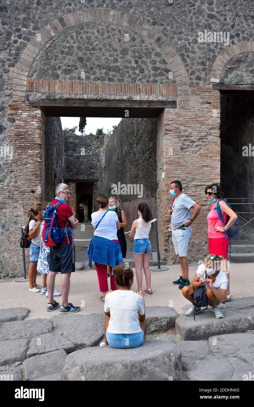 groups of tourists with masks in the ruins of the ancient Roman city ...