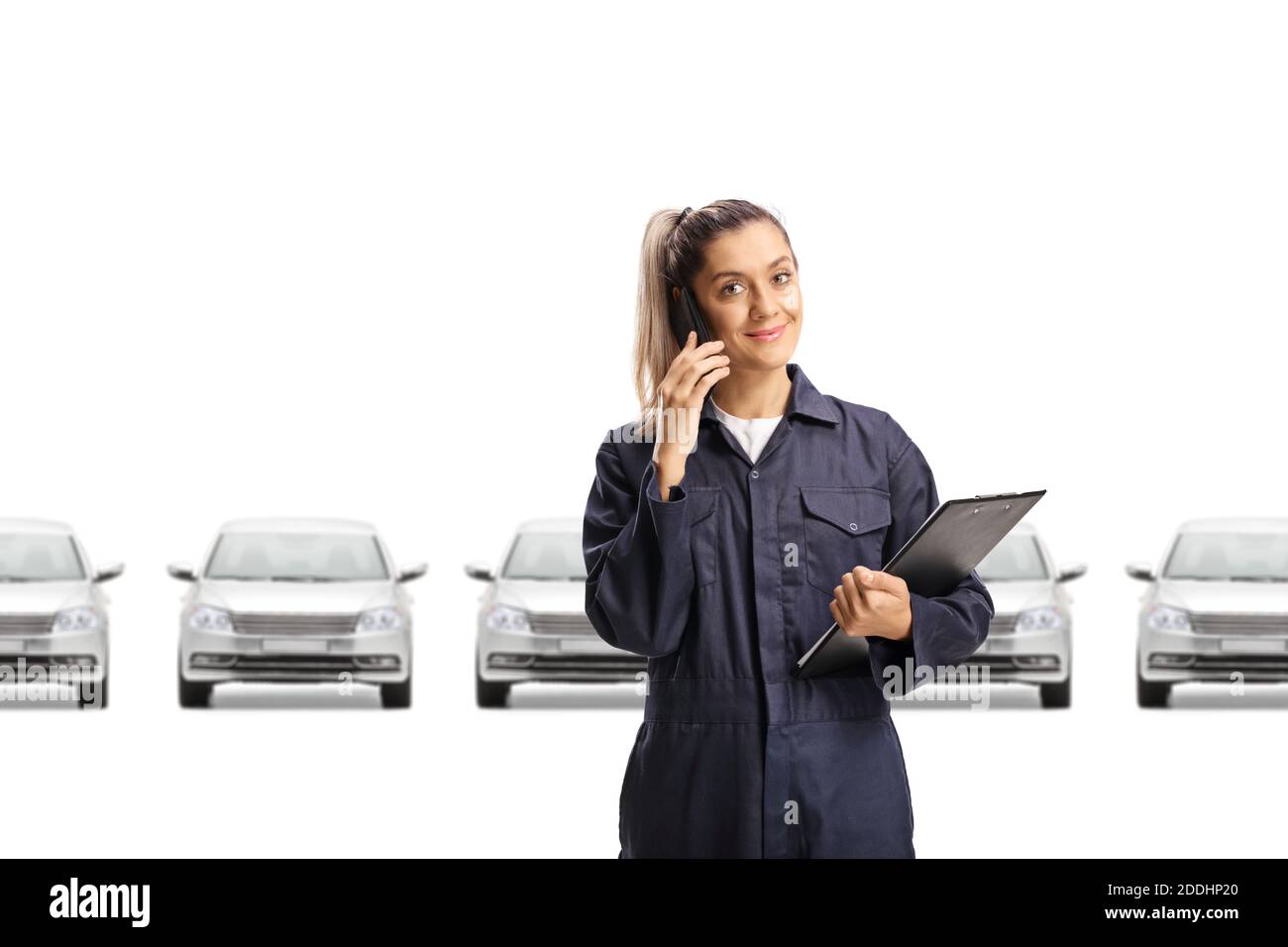 Female auto mechanic in a car showroom talking on a mobile phone ...