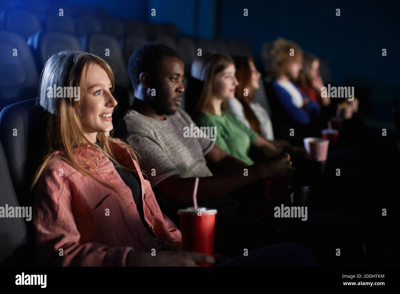 Selective focus of young smiling girl watching movie in cinema and ...