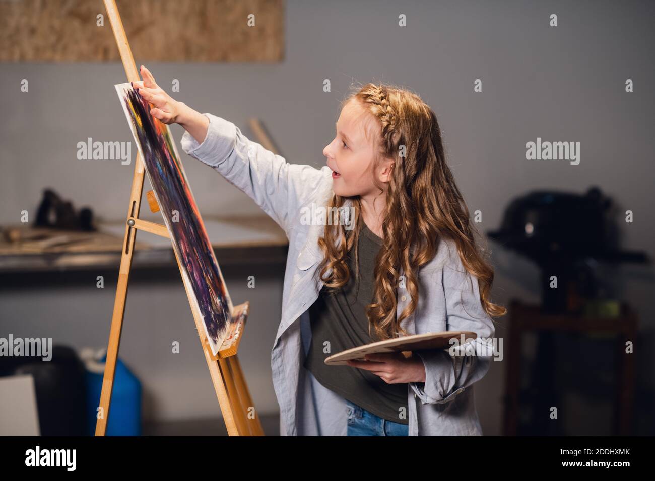 Young girl creative artist at work in a workshop. With passion draws a ...
