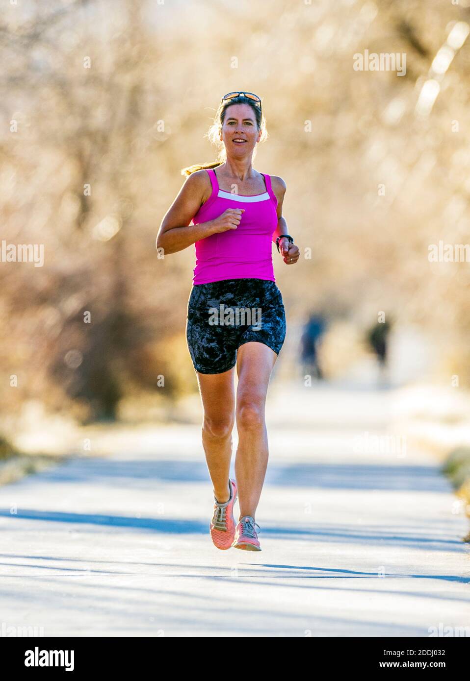 Attractive; middle-aged; fit woman running on paved trail; Salida ...