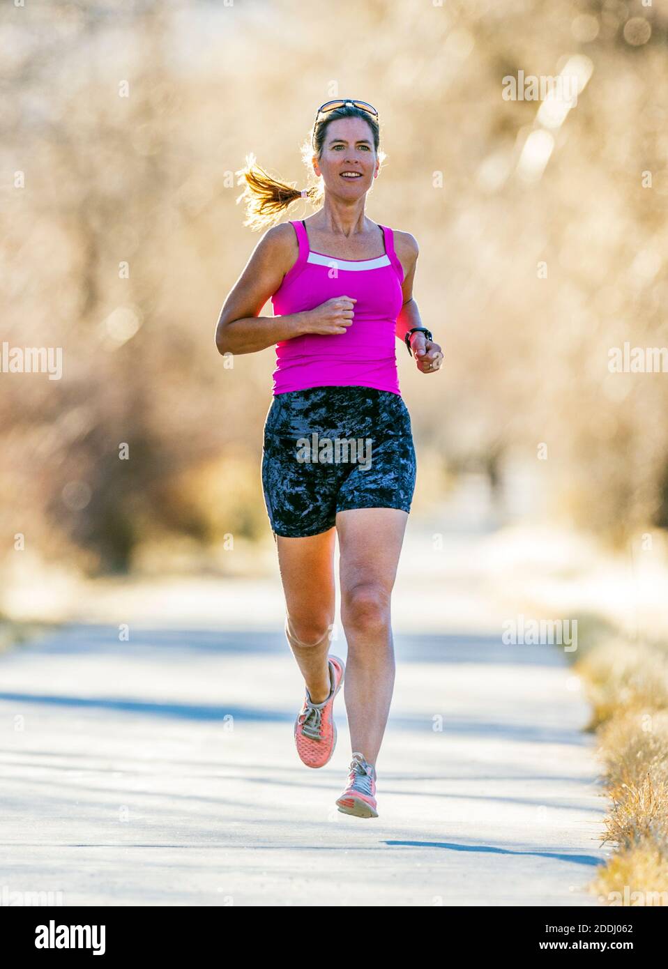 Attractive; middle-aged; fit woman running on paved trail; Salida ...