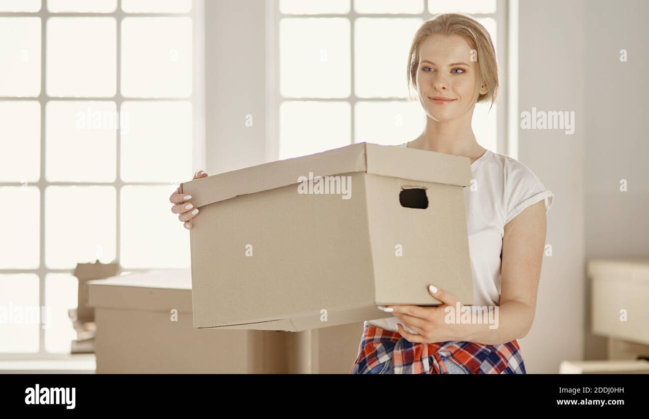 A beautiful single young woman unpacking boxes and moving into a new ...