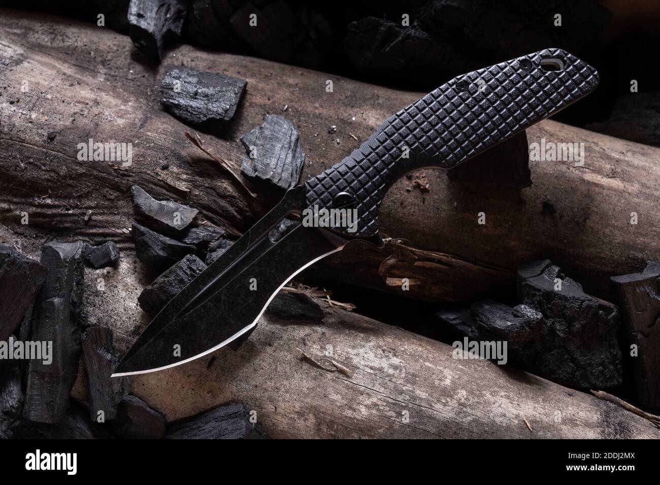 Knife with a curved blade. Black knife on a log. Knife with a black ...