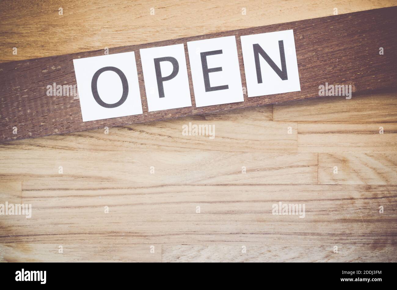 A top view of paper pieces with the word "OPEN" on wooden background ...