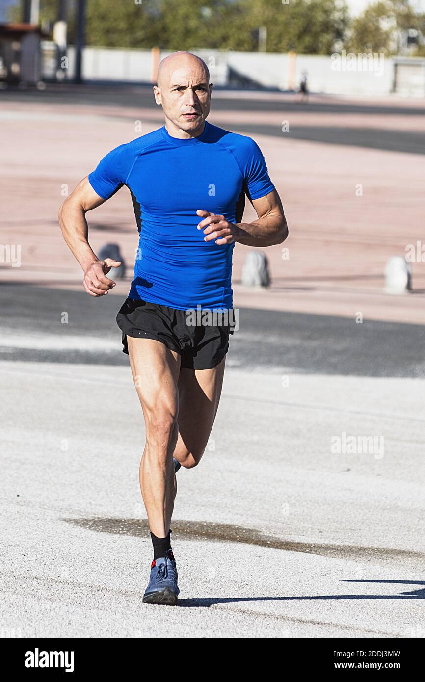 A bald muscular Caucasian athlete running outdoors on a sunny day Stock Photo - Alamy