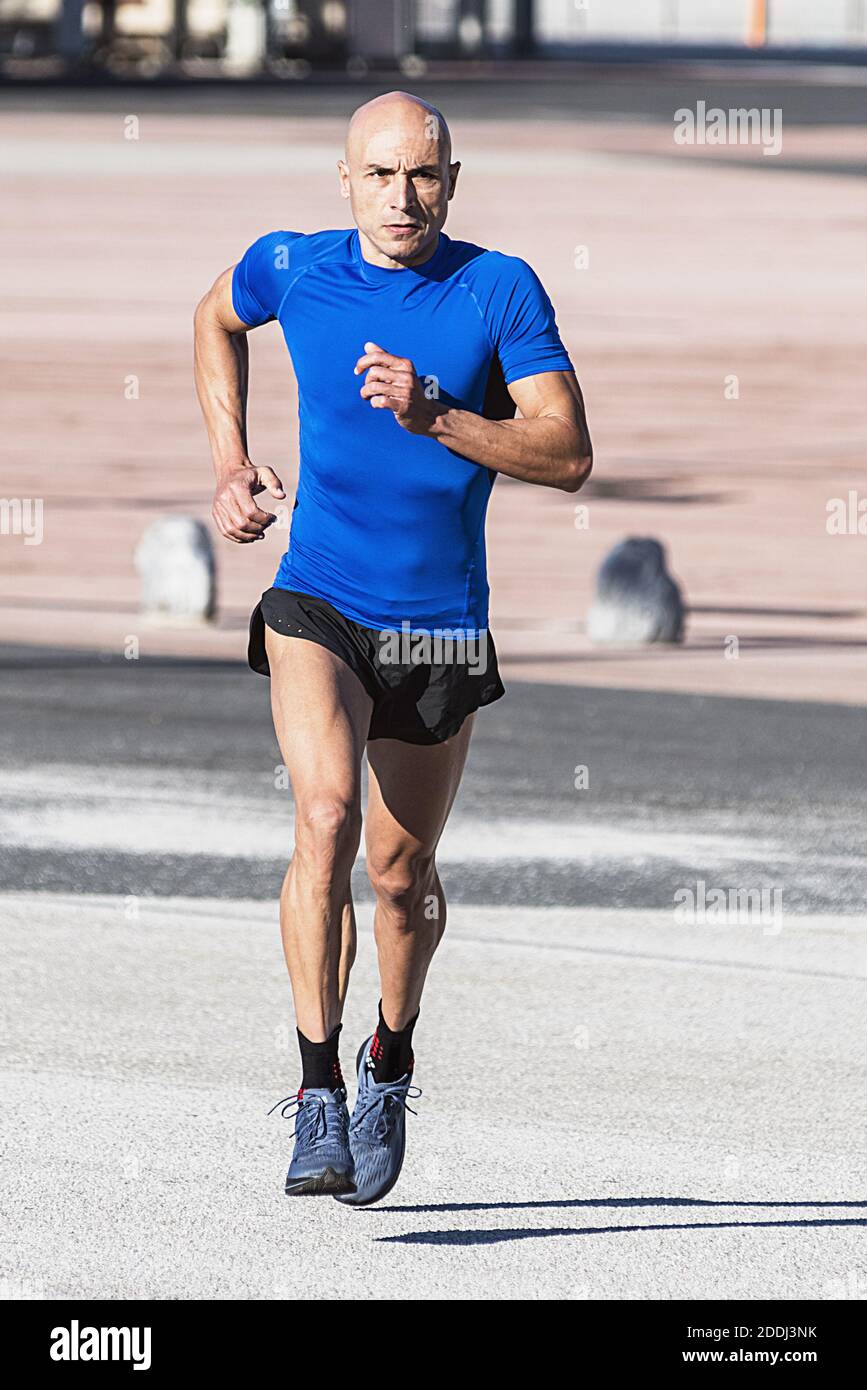 A bald muscular Caucasian athlete running outdoors on a sunny day Stock Photo - Alamy