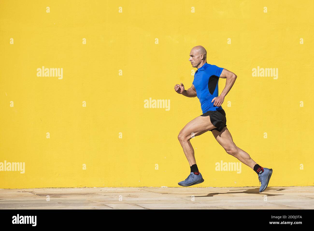 A side profile of a bald muscular Caucasian athletic runner against a ...