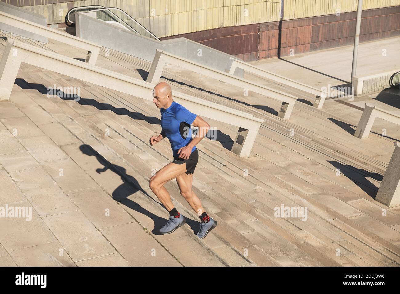 A bald muscular Caucasian athlete running on stadium steps Stock Photo ...