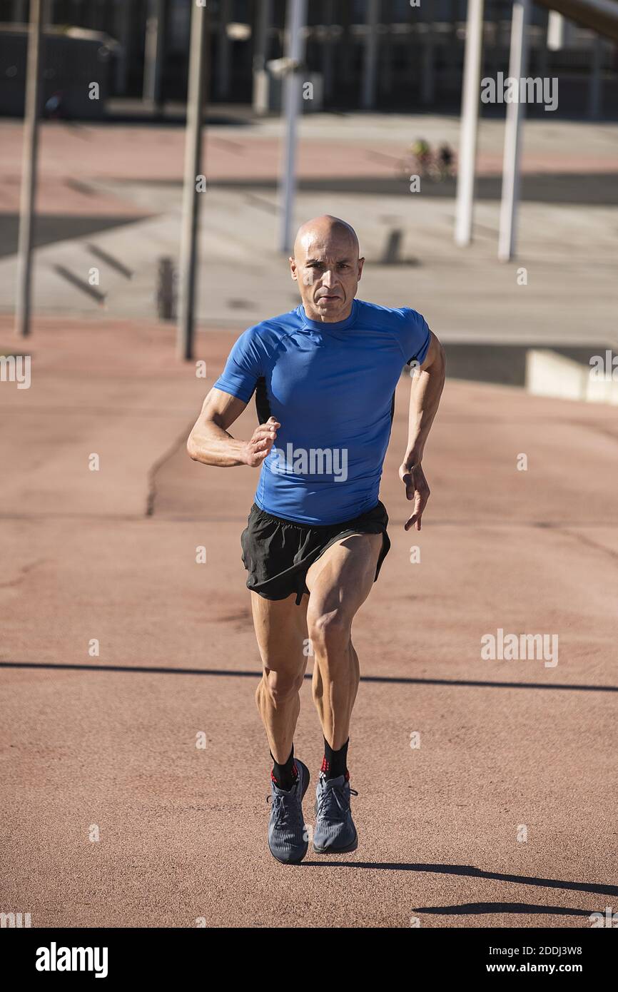 A bald muscular Caucasian athlete running outdoors on a sunny day Stock Photo - Alamy