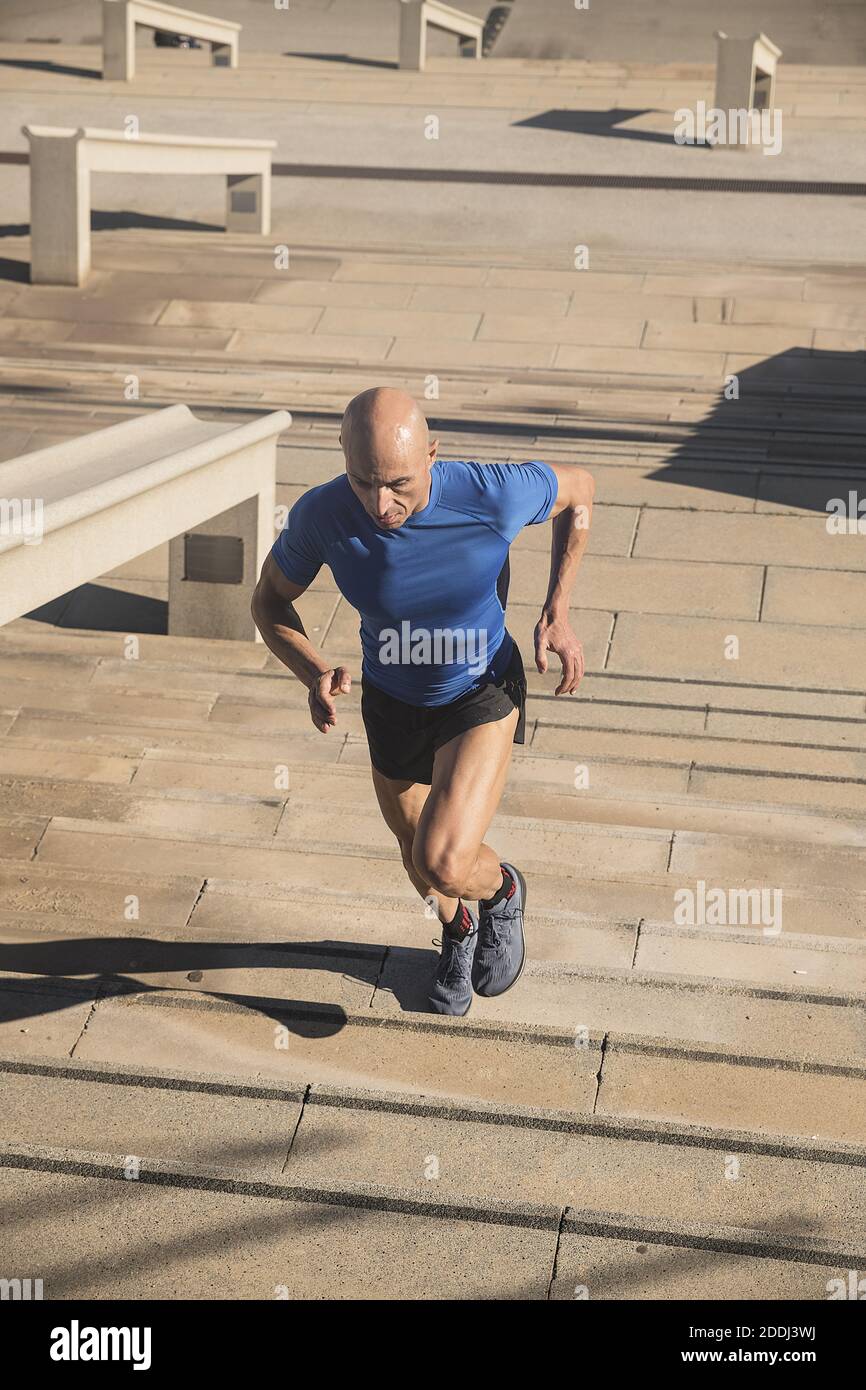 A vertical shot of a bald muscular Caucasian athlete running on stadium ...