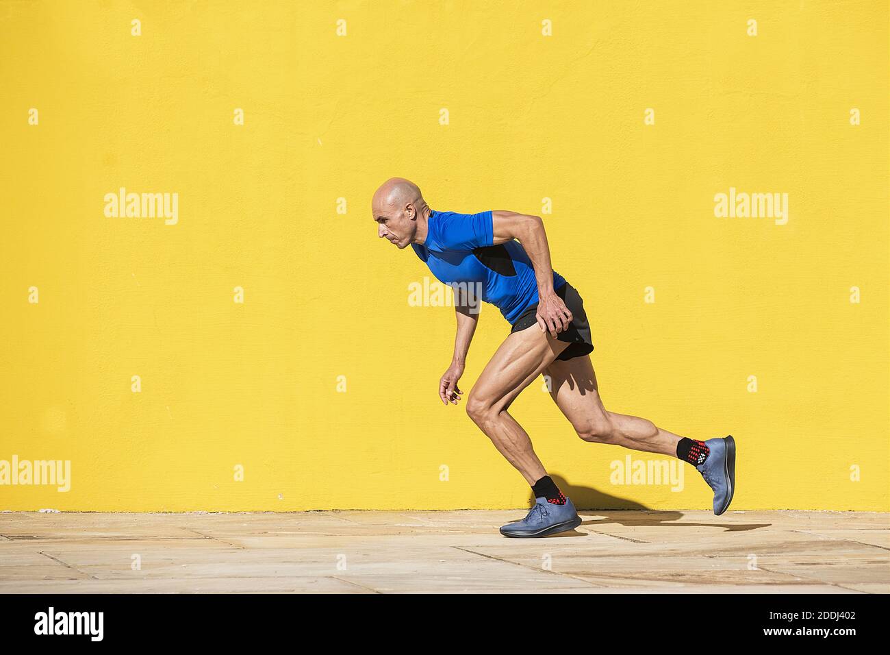 A side profile of a bald muscular Caucasian athletic runner against a ...