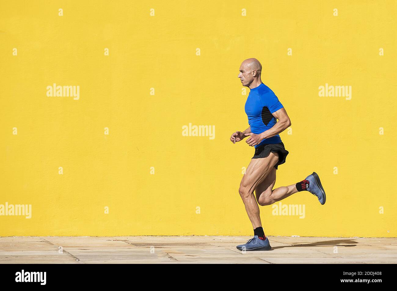 A side profile of a bald muscular Caucasian athletic runner against a ...