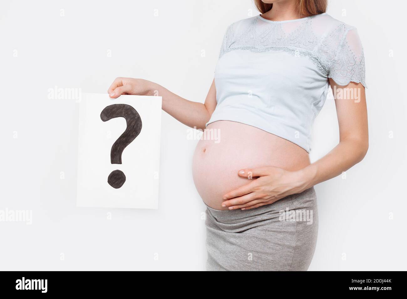 Image of a pregnant woman holding a paper with a question mark near the ...