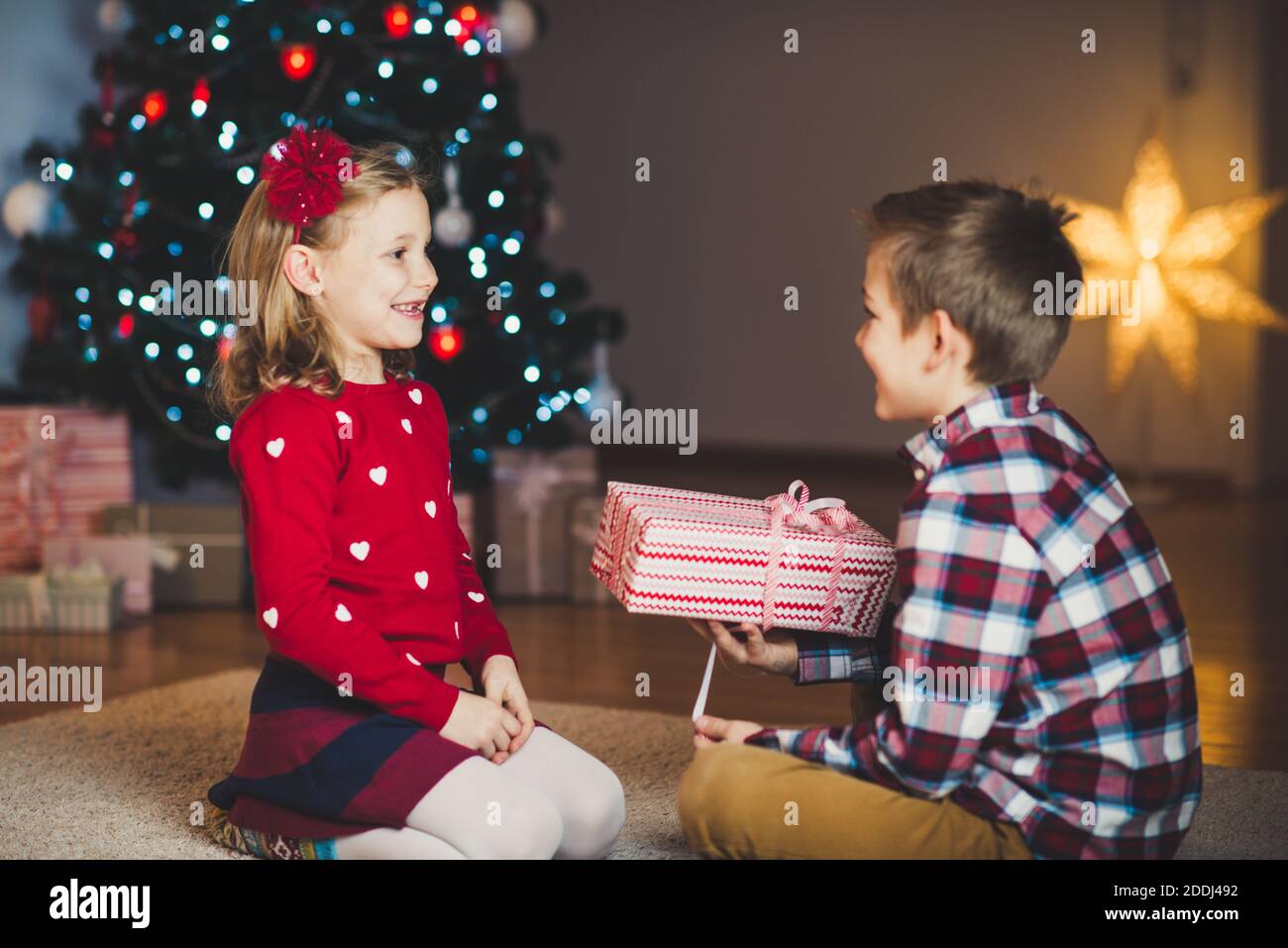 Two happy children in new year eve with presents near New Year Tree at ...