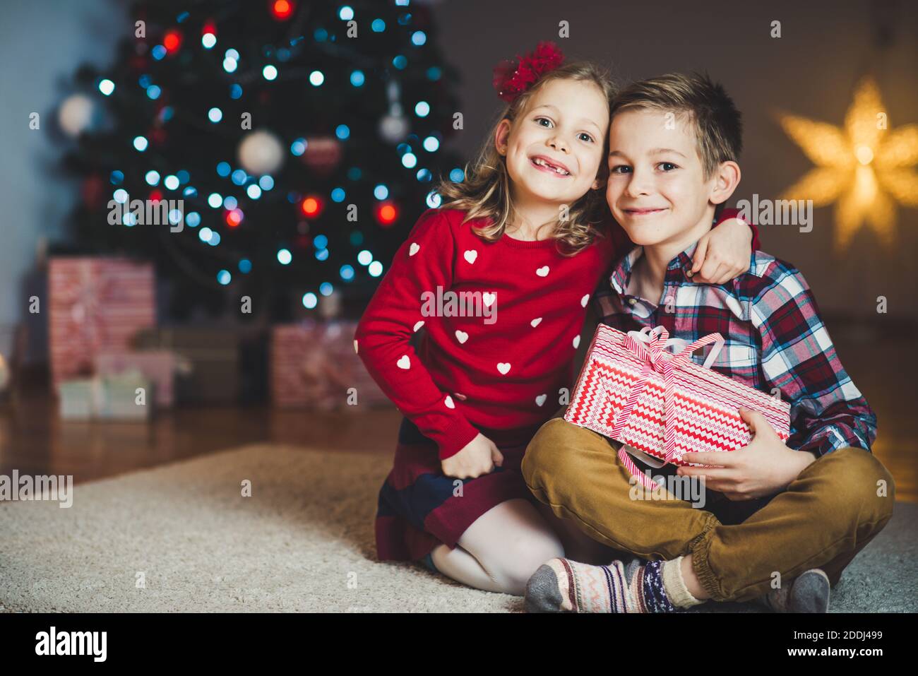 Two happy children in new year eve with presents near New Year Tree at ...