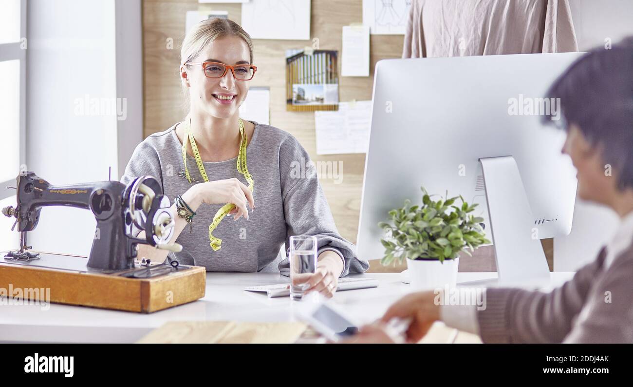 pretty dressmaker showing a new design to her client Stock Photo - Alamy