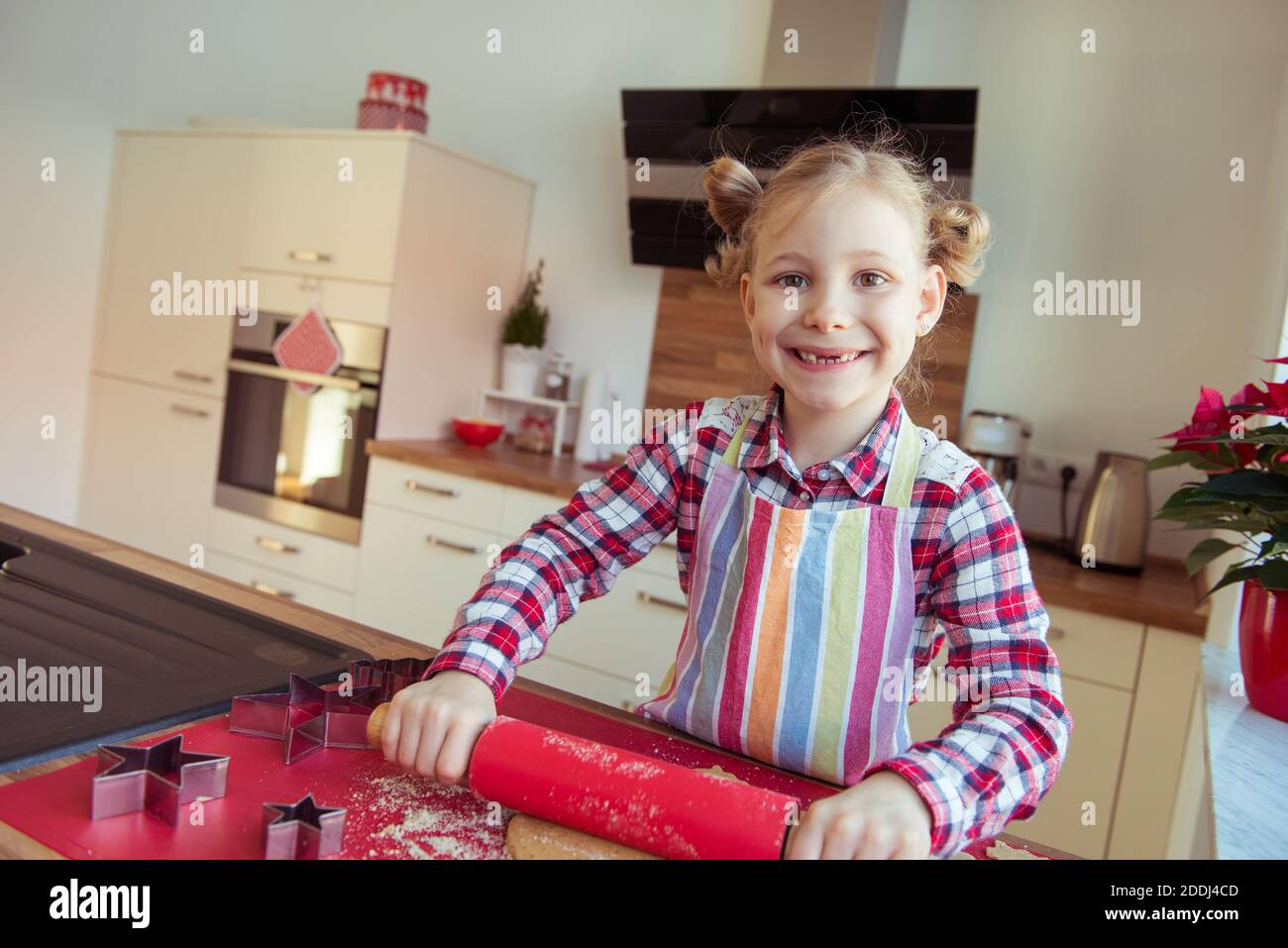 Pretty little girl with funny pigtails decoraiting christmas cookies of ...