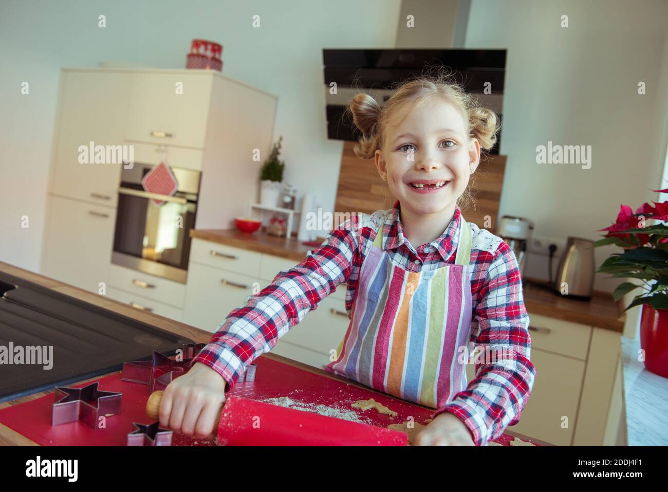 Pretty little girl with funny pigtails decoraiting christmas cookies of ...