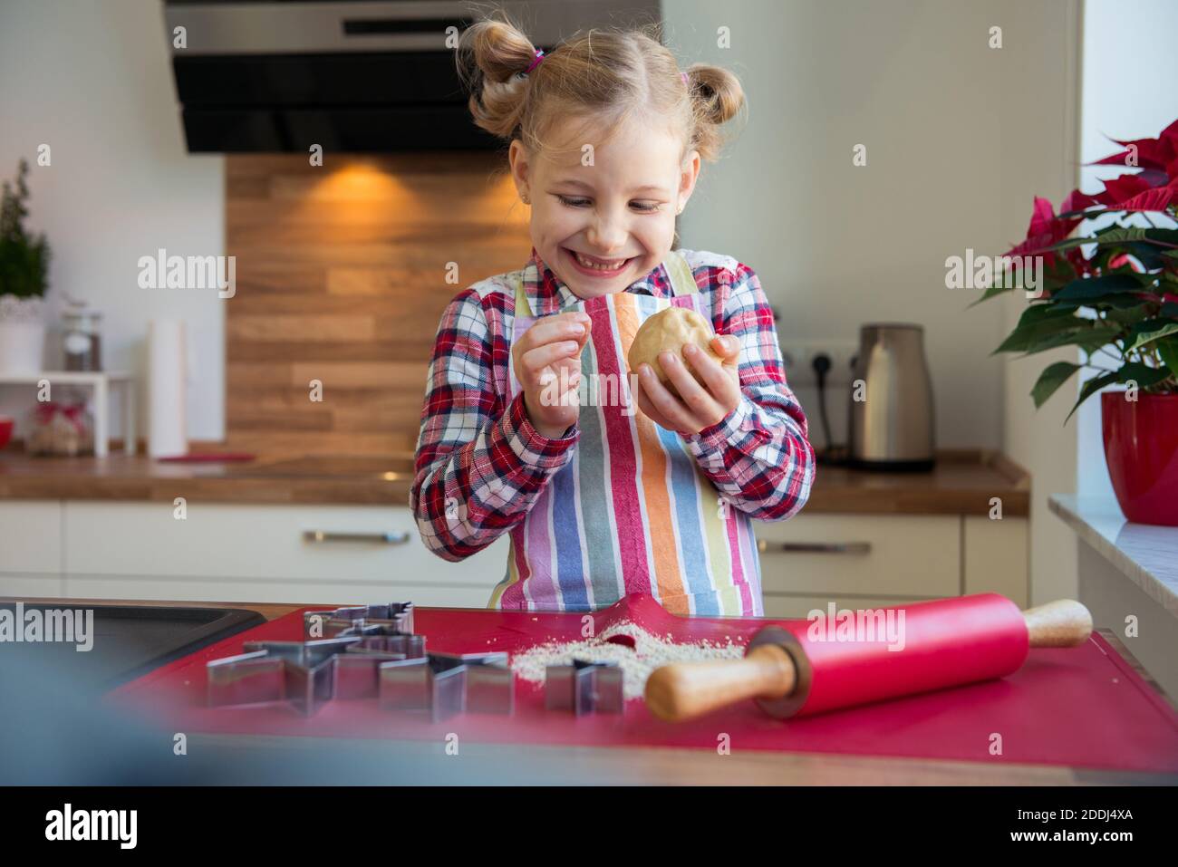 Pretty little girl with funny pigtails decoraiting christmas cookies of ...