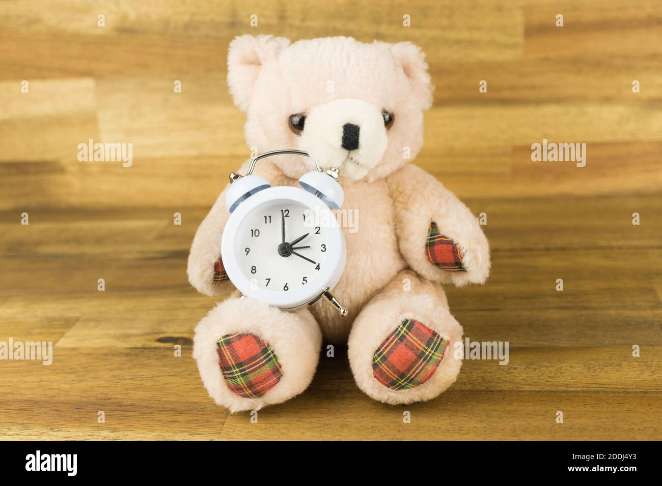 A cute teddy bear with an alarm clock on a wooden surface Stock Photo ...
