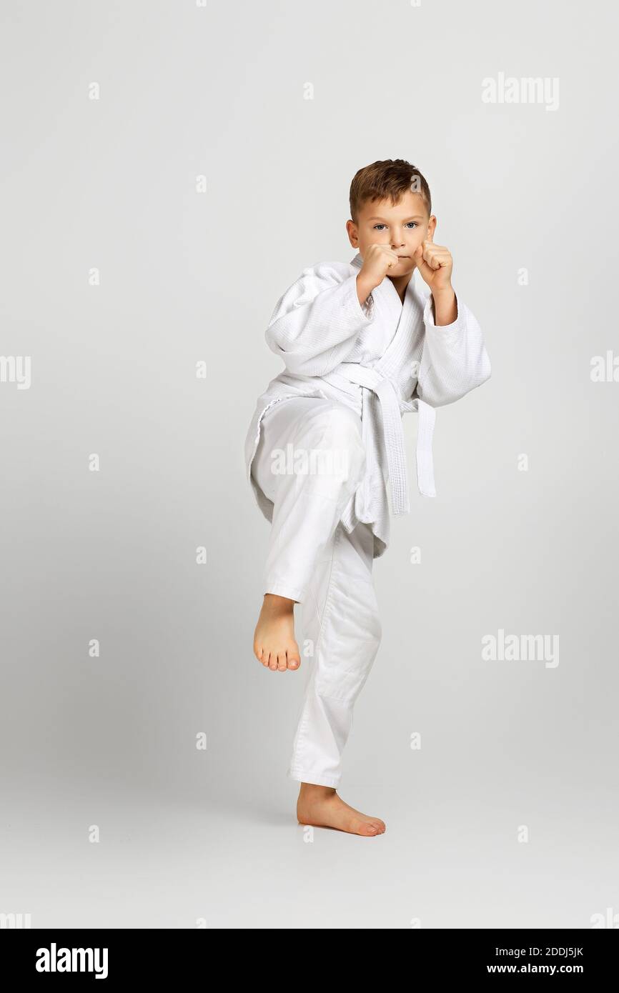 little child boy in a white karate kimono training. Full length ...